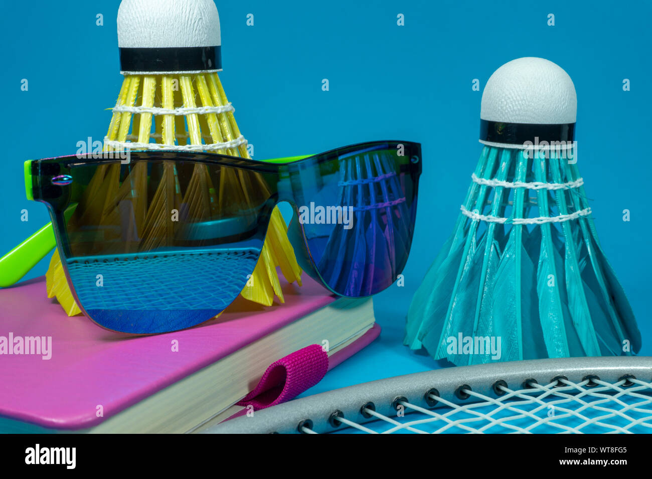 Colorful badminton shuttlecocks with racket and sunglasses resting on a ...