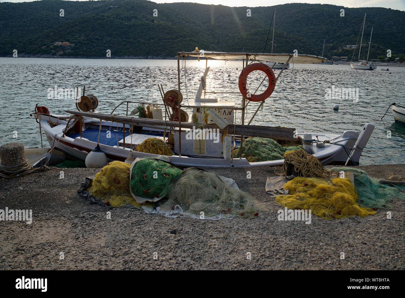 Fishing nets on the quay and boat in the background Stock Photo - Alamy