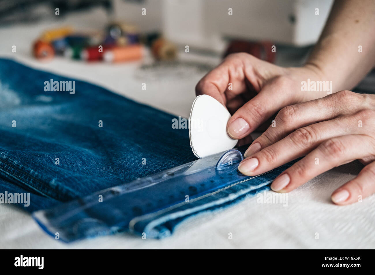 Seamstress marking hem on a pair of jeans in tailor shop Stock Photo ...