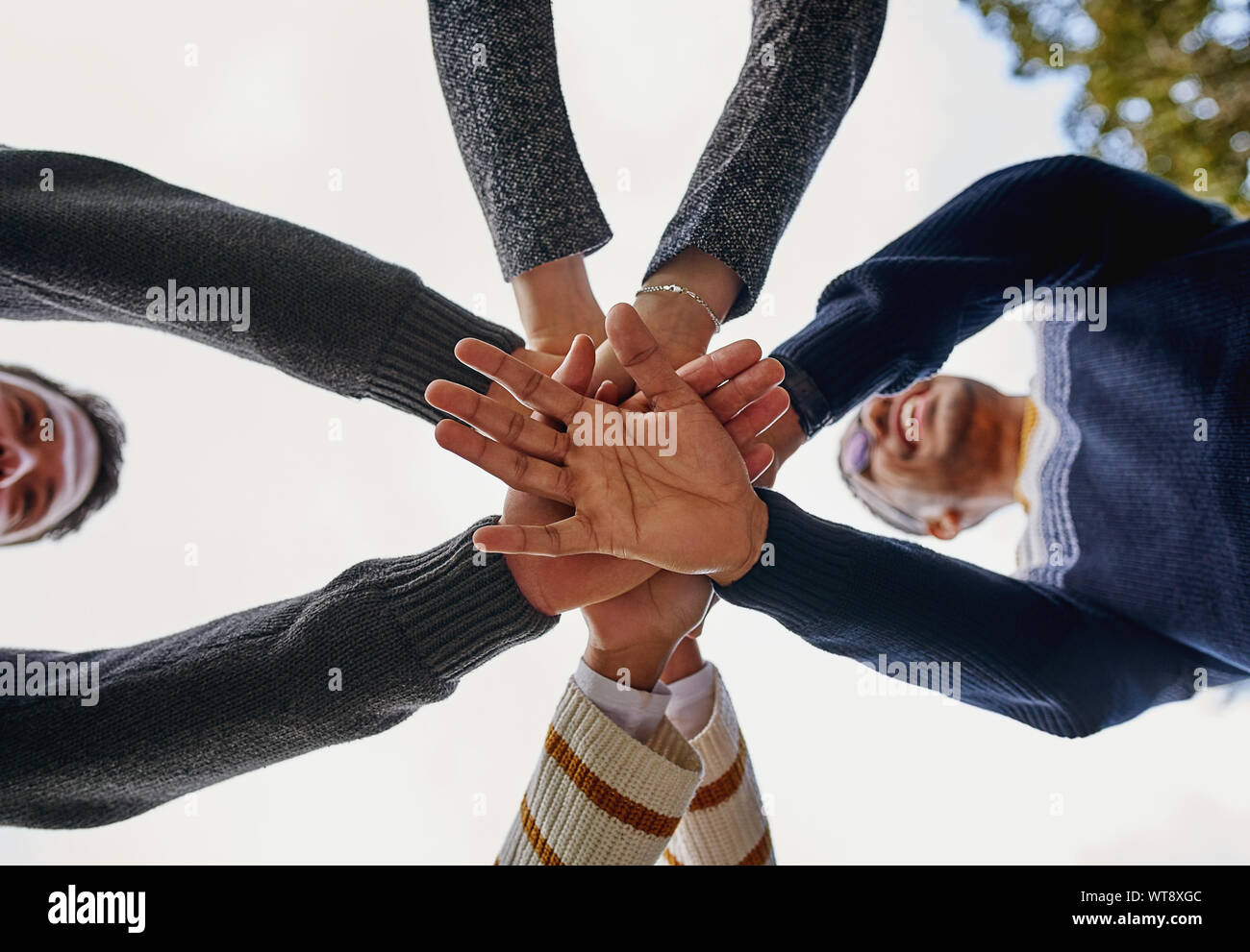 Low angle view of diverse friends stacked hands together showing ...