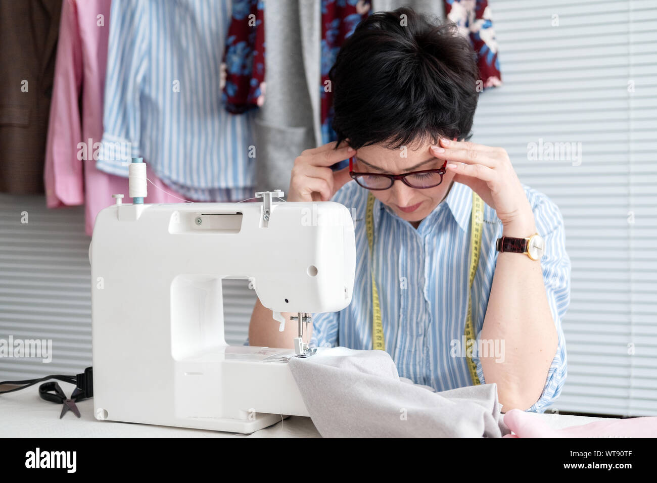 Frustrated tired seamstress touching her head, feeling absolutely ...