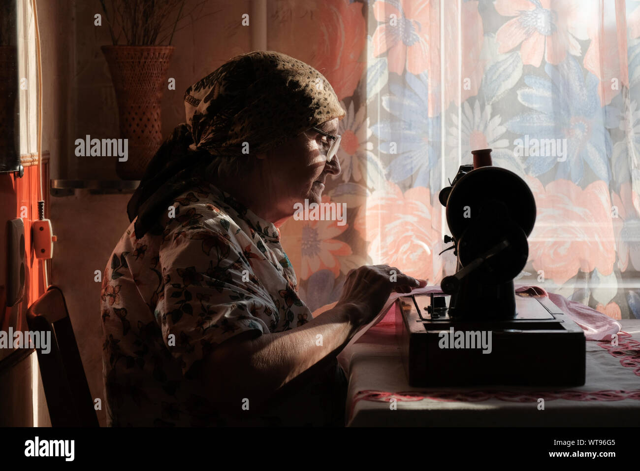 Senior woman in spectacles use sewing machine, silhouette of old ...
