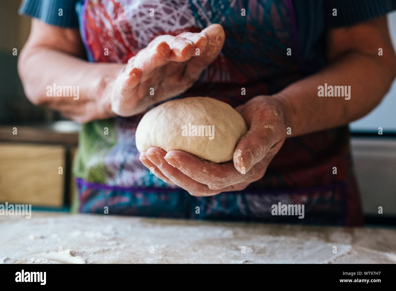 Wrinkled grandmothers hands holding and kneading fresh bread dough ...