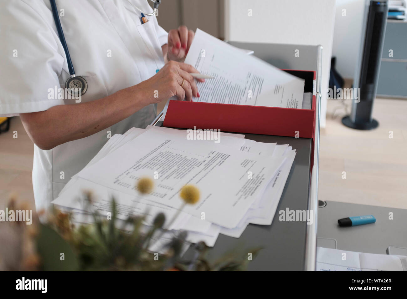 Doctor sorting out paperwork at her desk Stock Photo - Alamy
