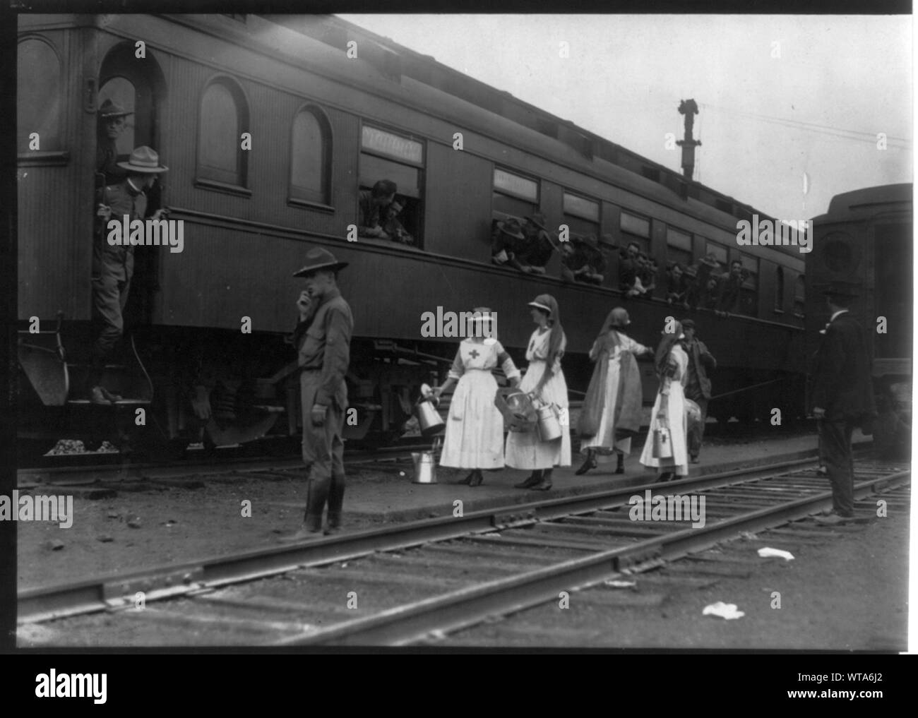 Men on troops train, with Red Cross workers in front, probably in ...