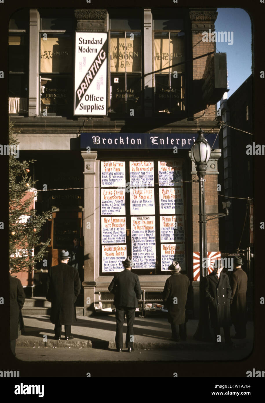 Men reading headlines posted in street-corner of Brockton Enterprise ...