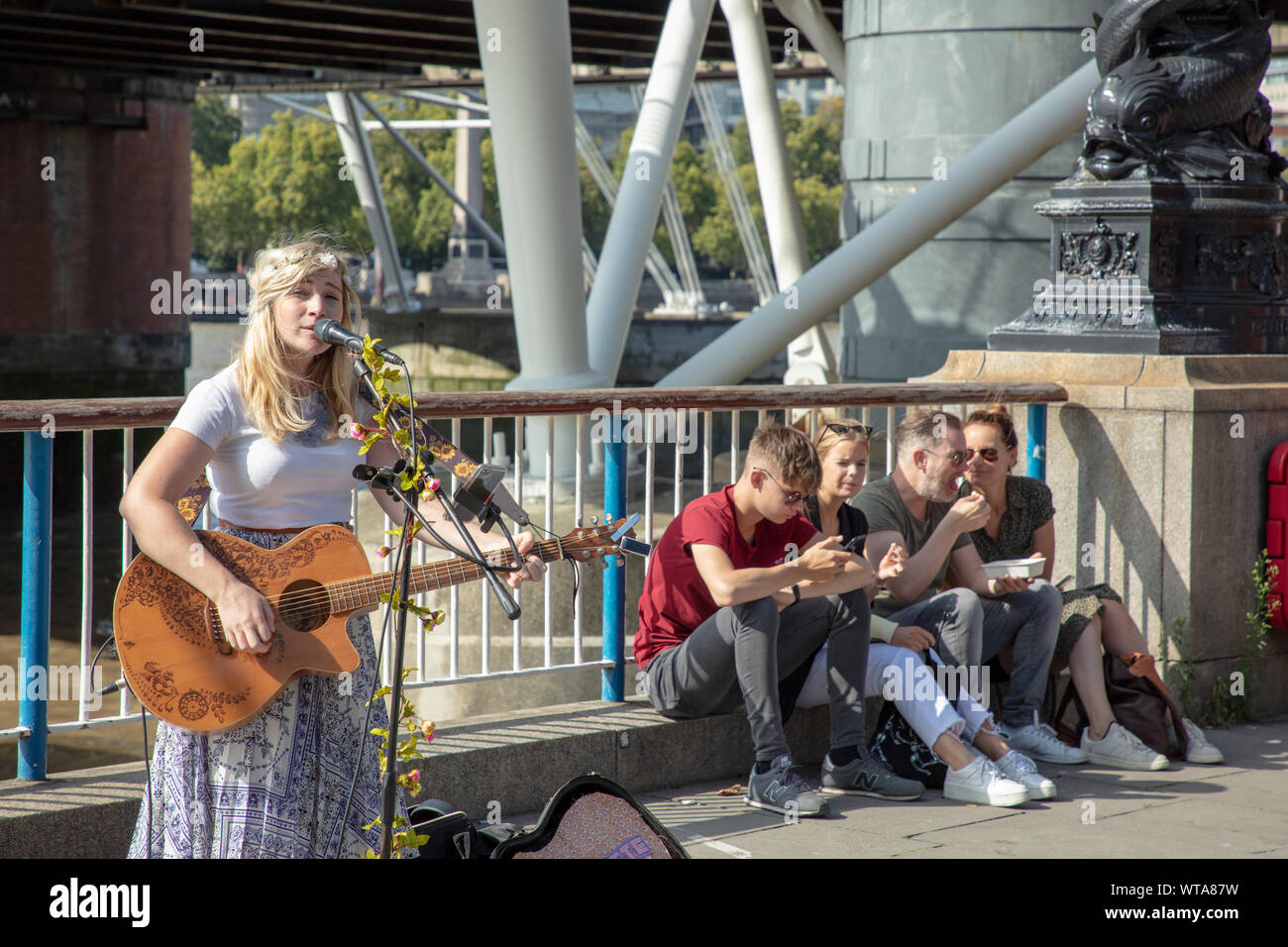 Busker singer with guitar on the Southbank of London with a family of ...