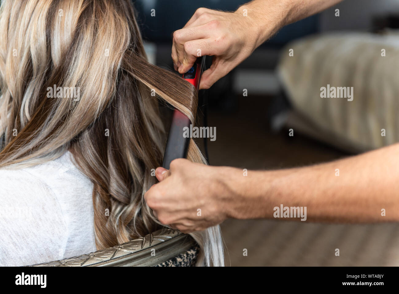Long hair of woman seated in chair being styled with skilled hands ...