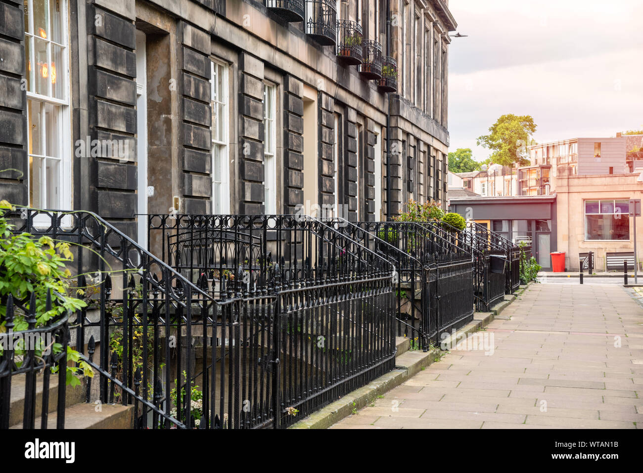 Exterior of old stone terraced houses with doorsteps and metal fences ...