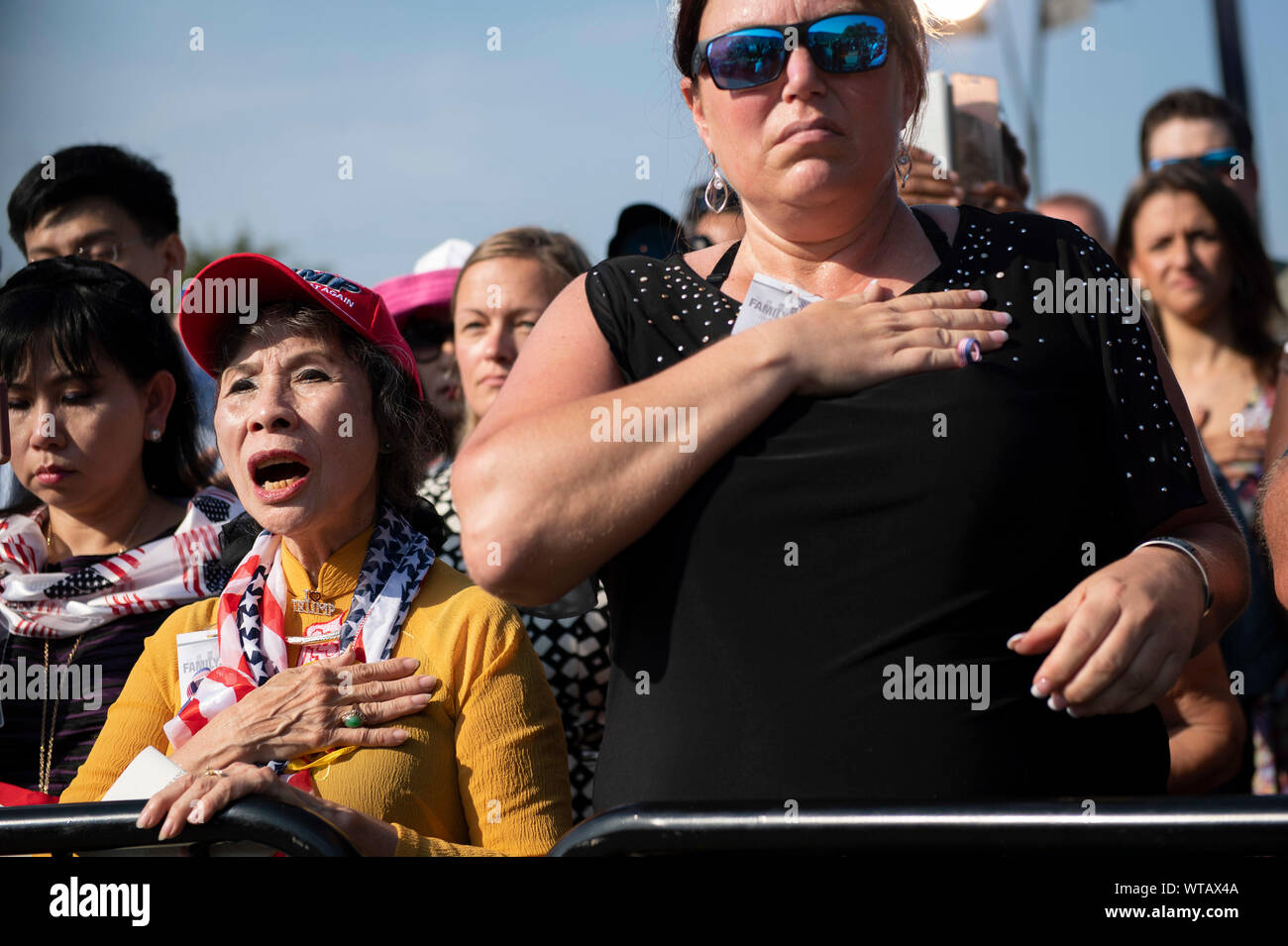Audience members stand for the National Anthem at a ceremony at the ...