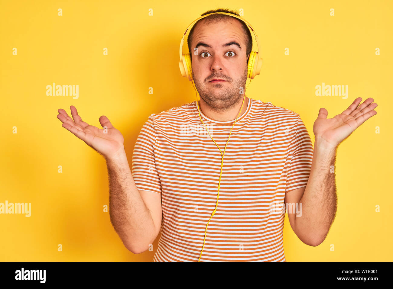 Young man listening to music using headphones standing over isolated ...