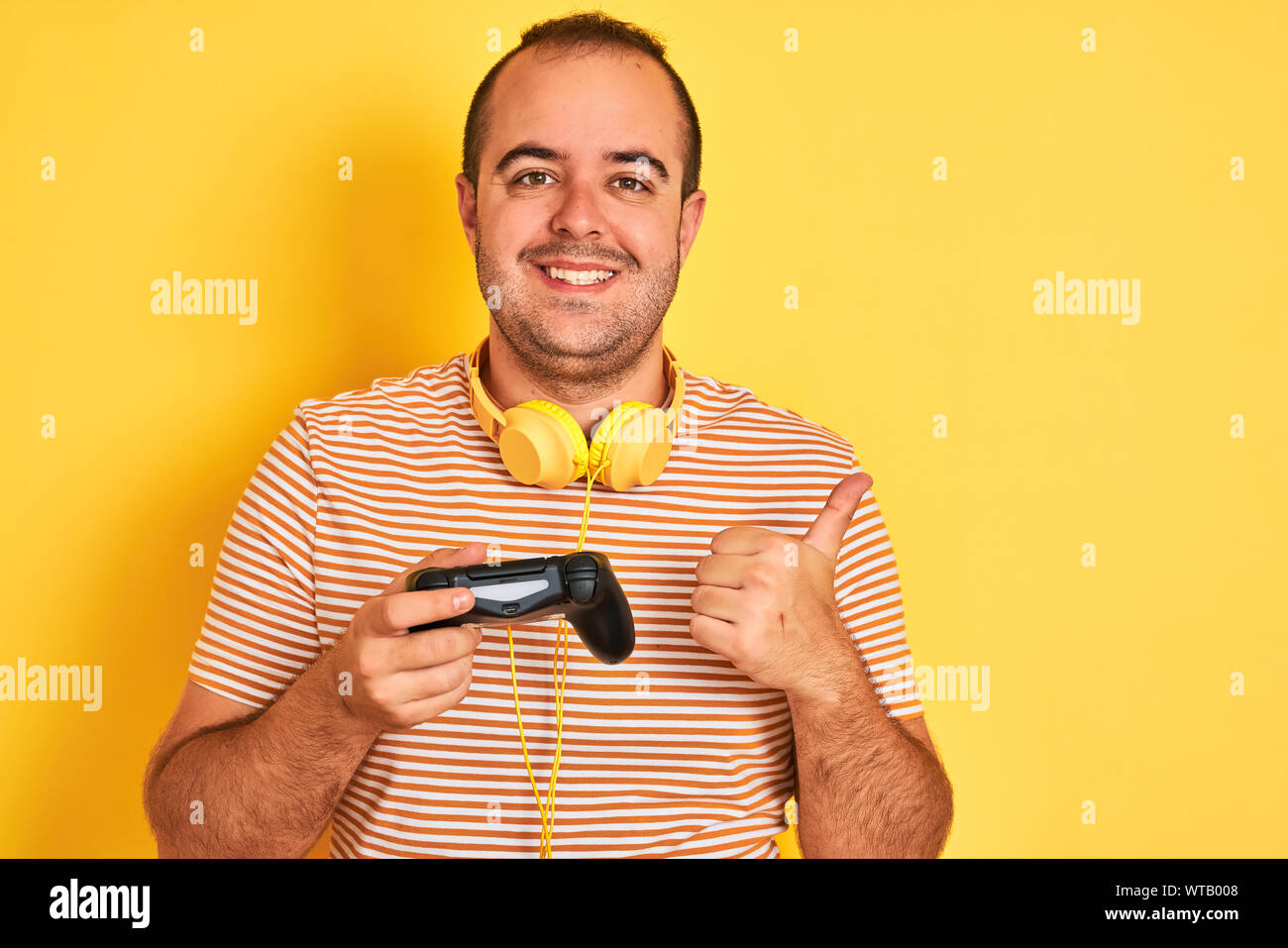 Young gamer man playing video game using headphones over isolated ...