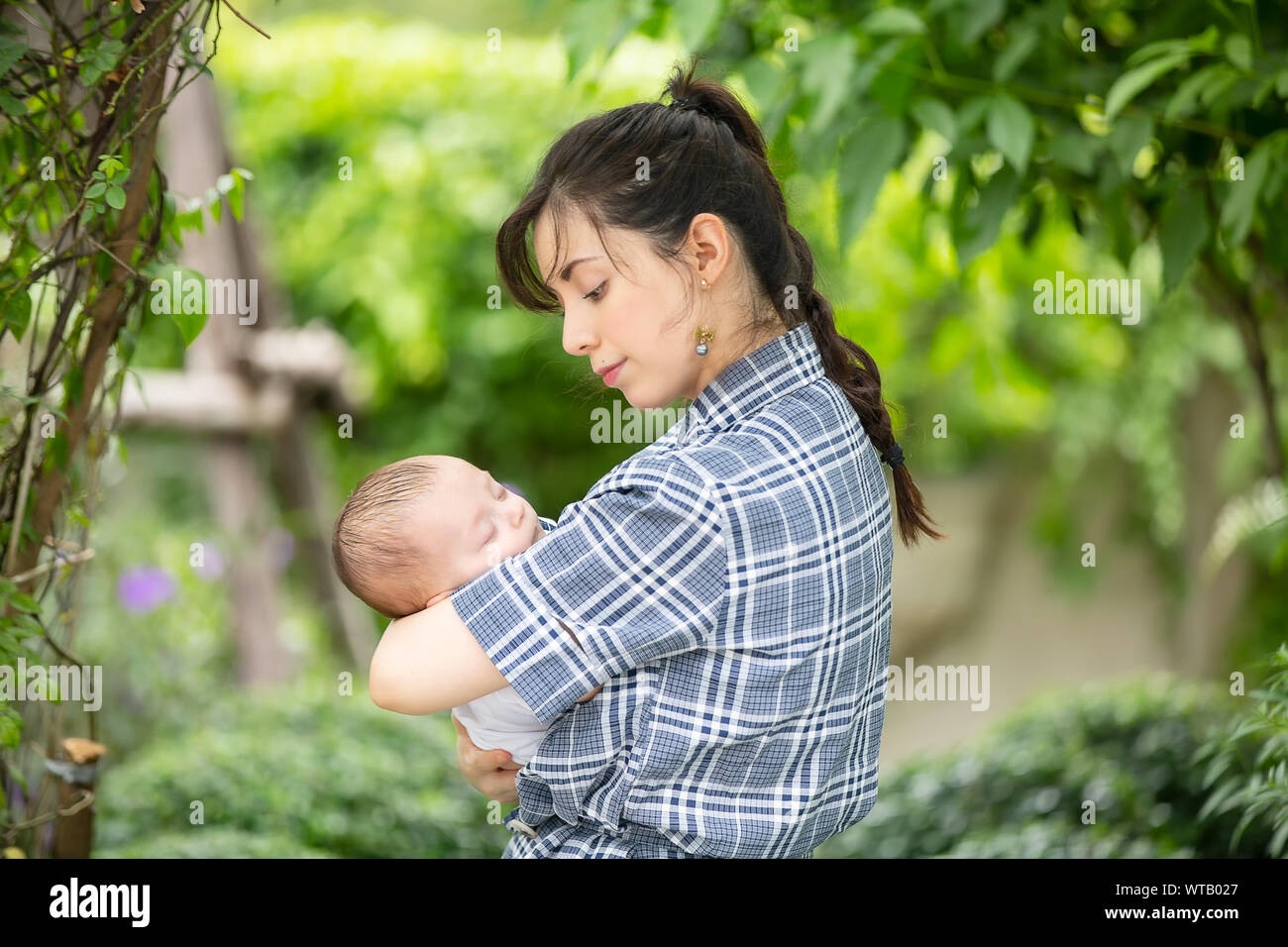 Portrait Of Mother Carrying Son While Standing Against Plants Stock ...