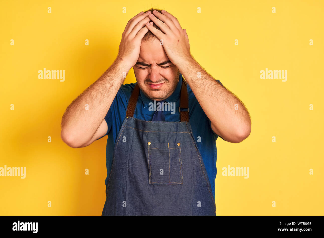 Young shopkeeper man wearing apron standing over isolated yellow ...