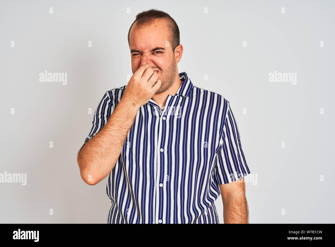 Young man wearing blue striped shirt standing over isolated white ...