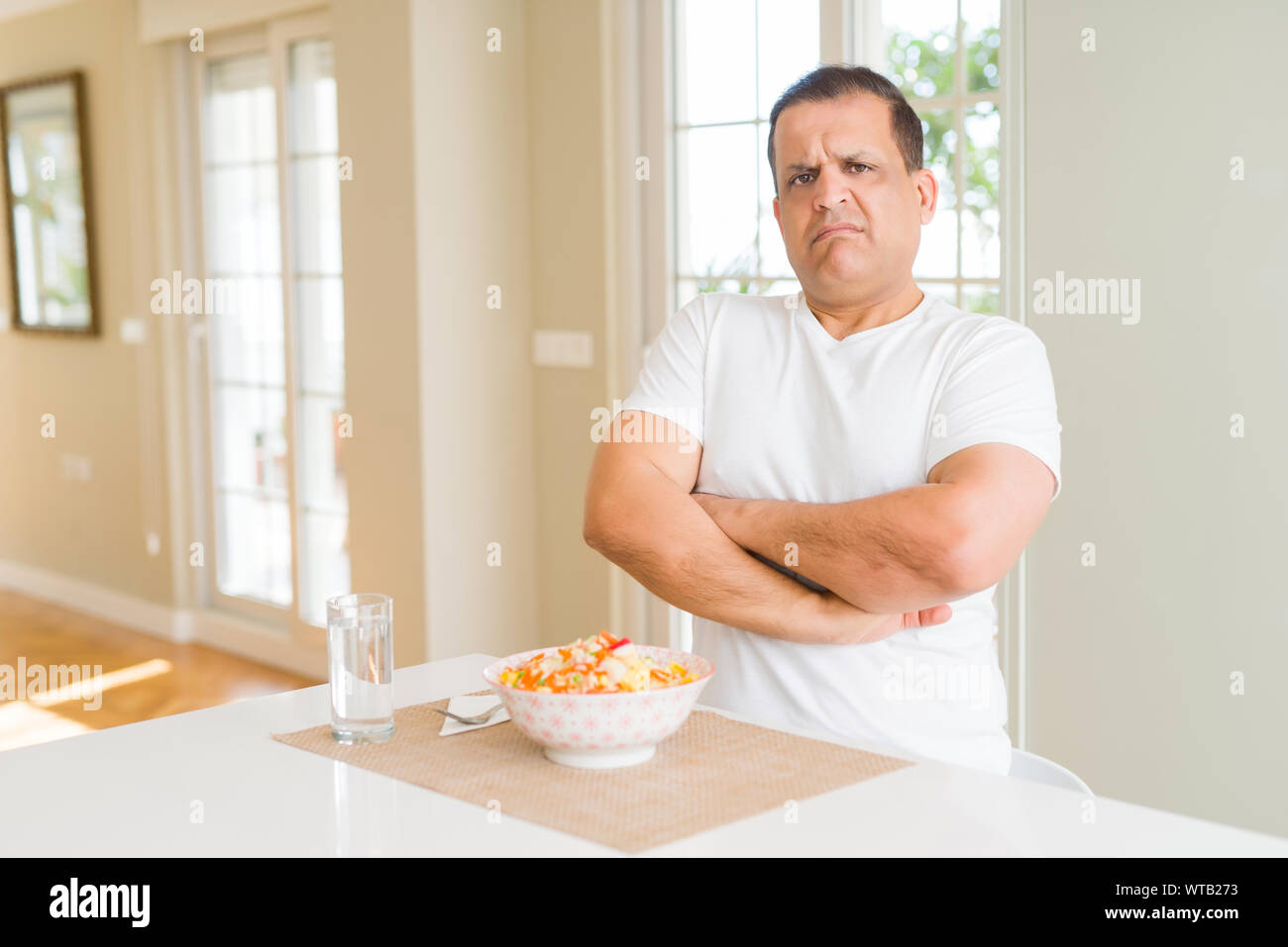 Middle age man eating rice at home skeptic and nervous, disapproving ...