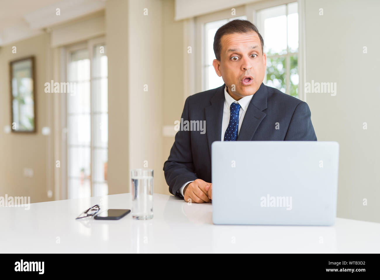 Middle age business man working with computer laptop afraid and shocked ...