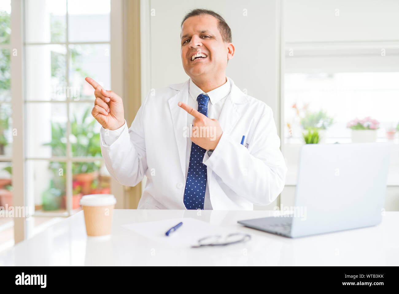 Middle age doctor man wearing white medical coat working with laptop at ...
