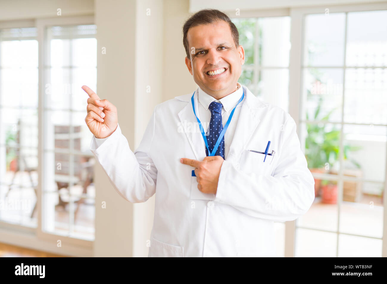 Middle age doctor man wearing medical coat and id card badge over white ...