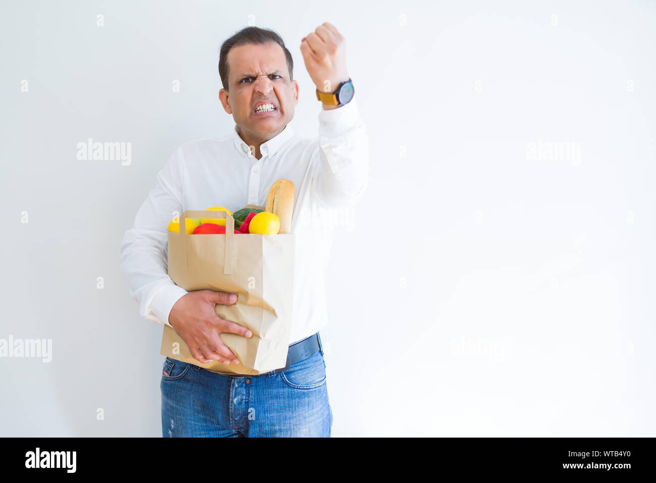 Middle age man holding groceries shopping bag over white background ...