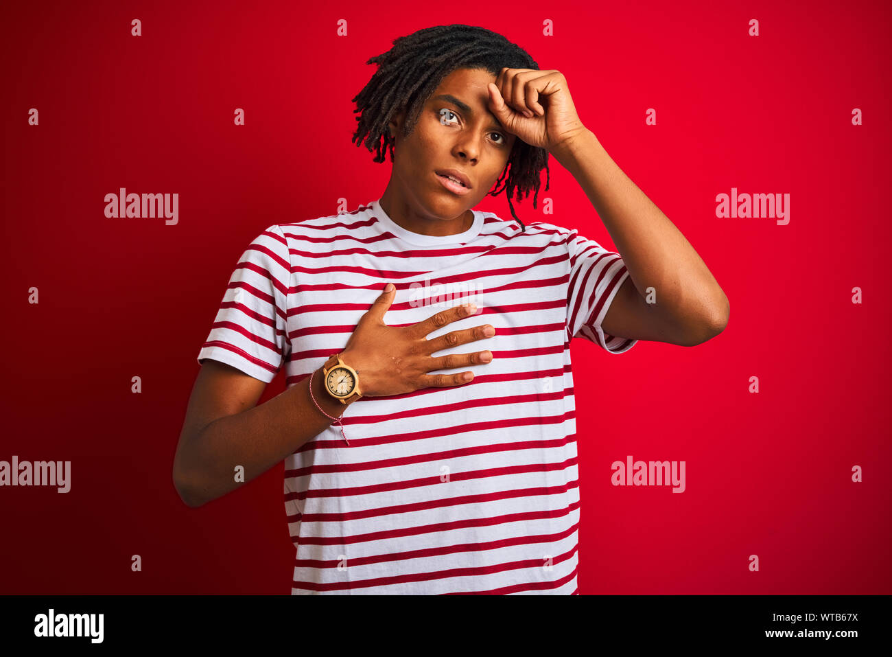 Young afro man with dreadlocks wearing striped t-shirt standing over ...
