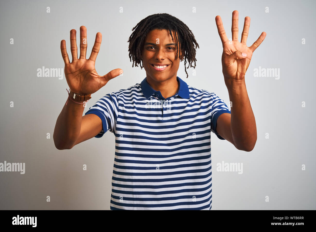 Afro man with dreadlocks wearing striped blue polo standing over ...