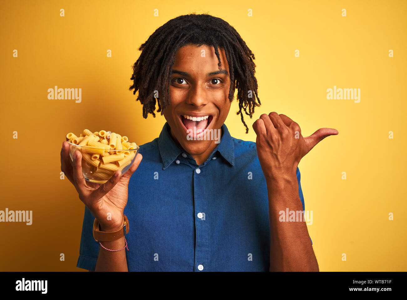 Afro american man with dreadlocks holding pasta macaroni over isolated ...