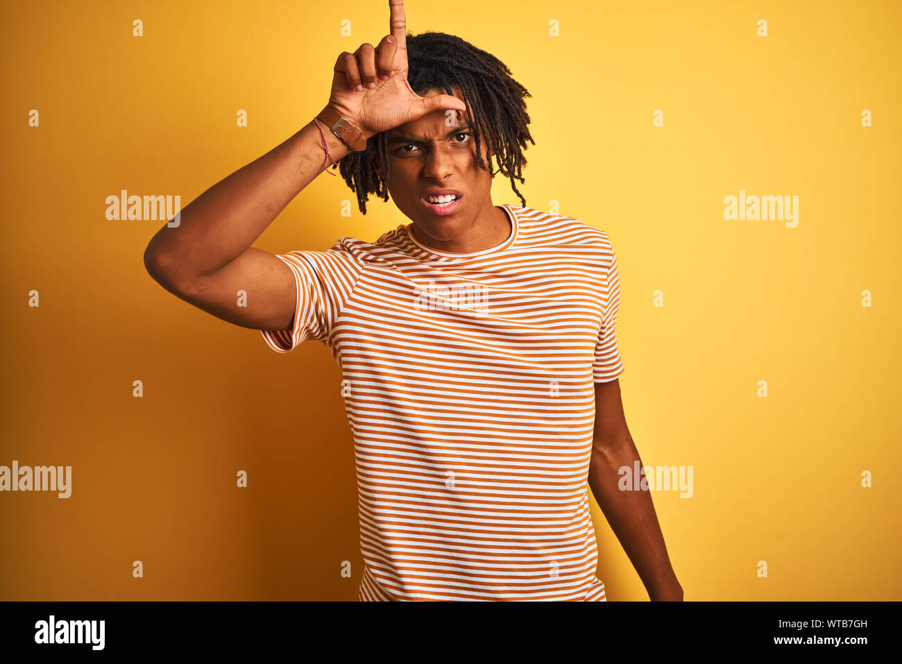 Afro man with dreadlocks wearing striped t-shirt standing over isolated ...