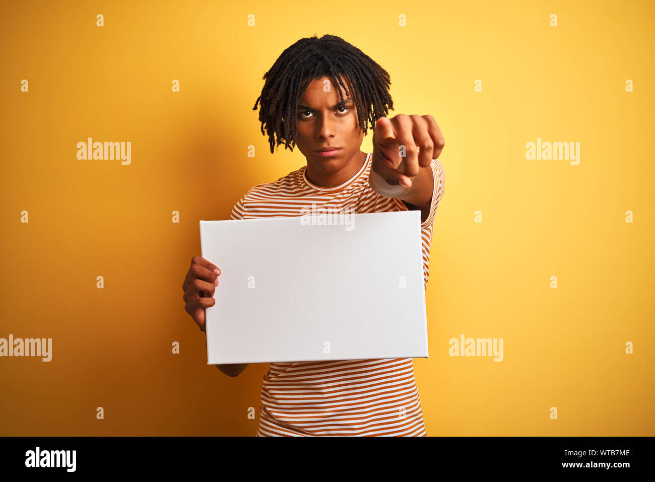 Afro american man with dreadlocks holding banner over isolated yellow ...