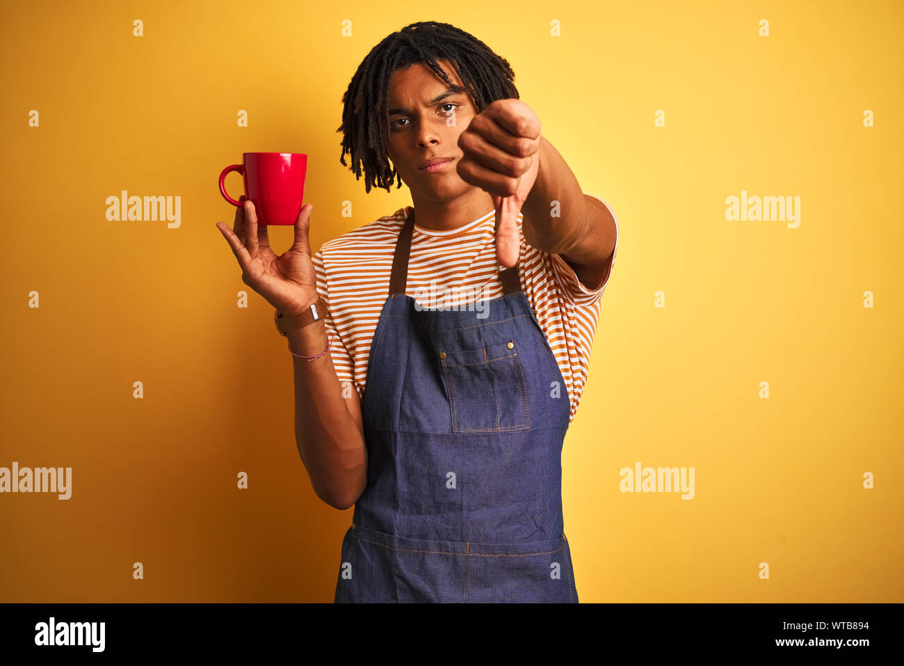 Afro barista man with dreadlocks drinking cup of coffee over isolated ...