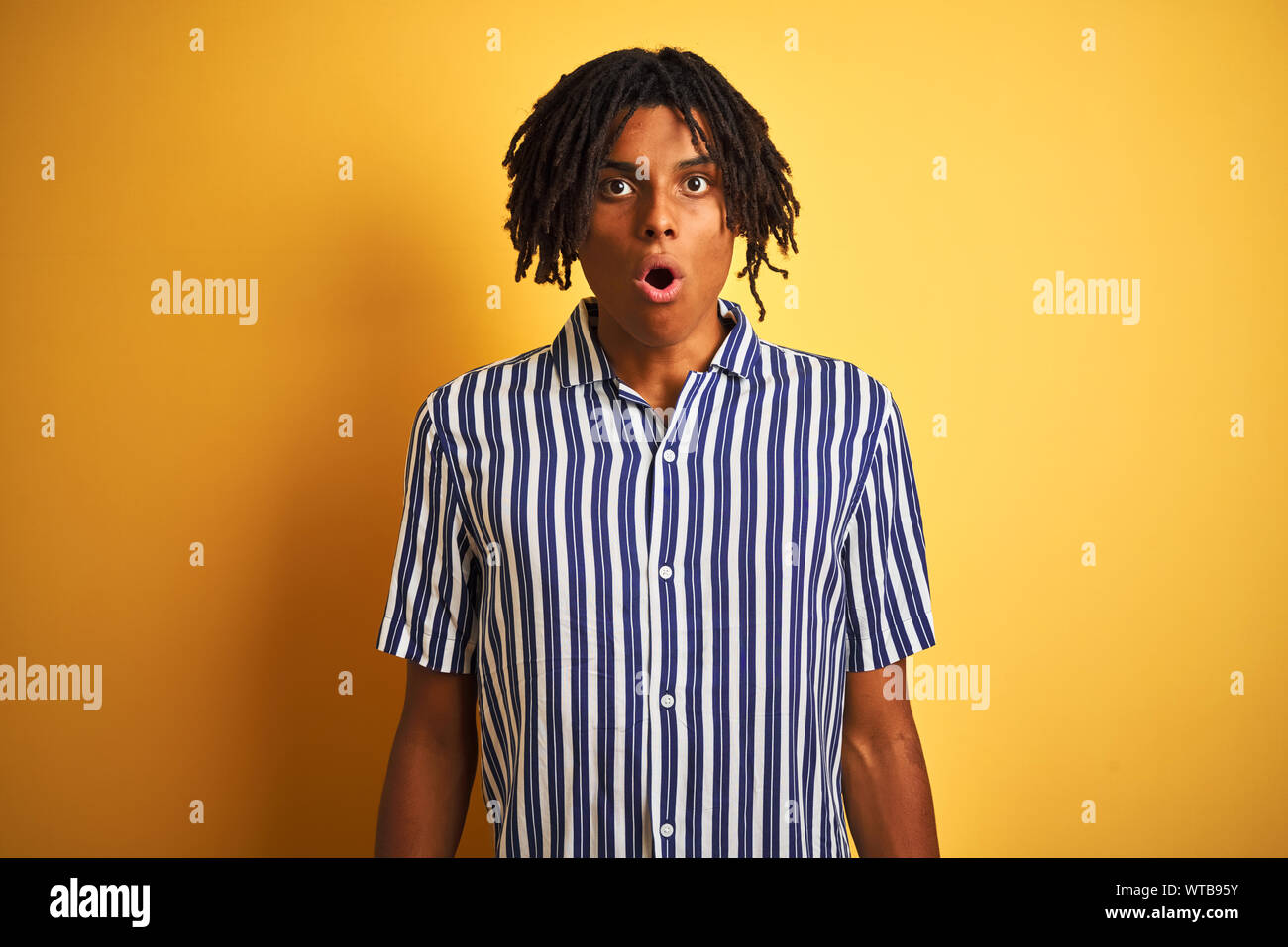 Afro man with dreadlocks wearing casual striped t-shirt over isolated ...