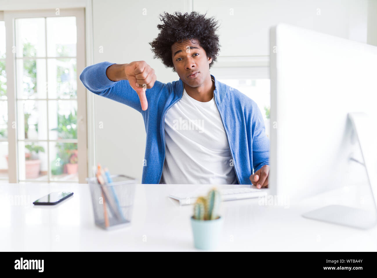 African American man working using computer with angry face, negative ...
