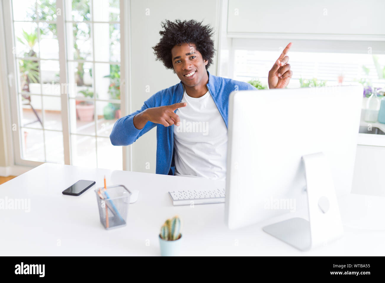 African American man working using computer smiling and looking at the ...