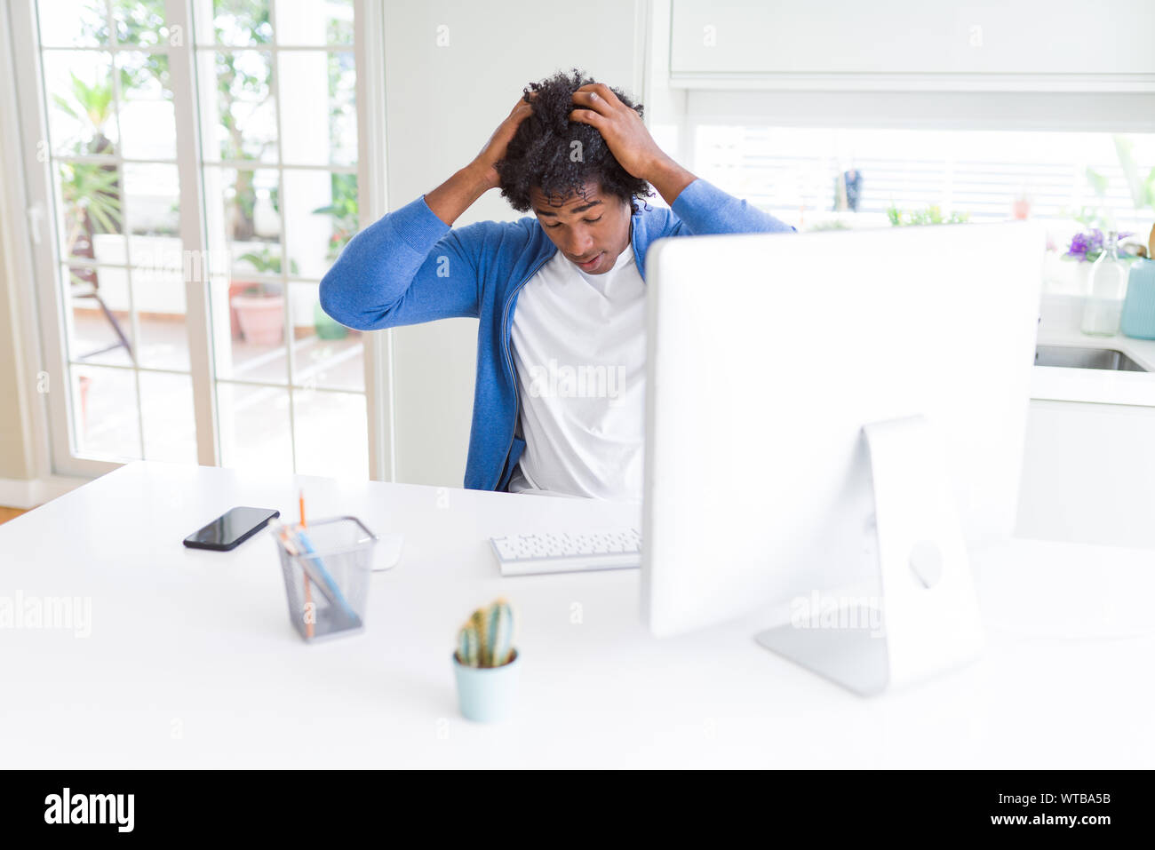 African American man working using computer suffering from headache ...