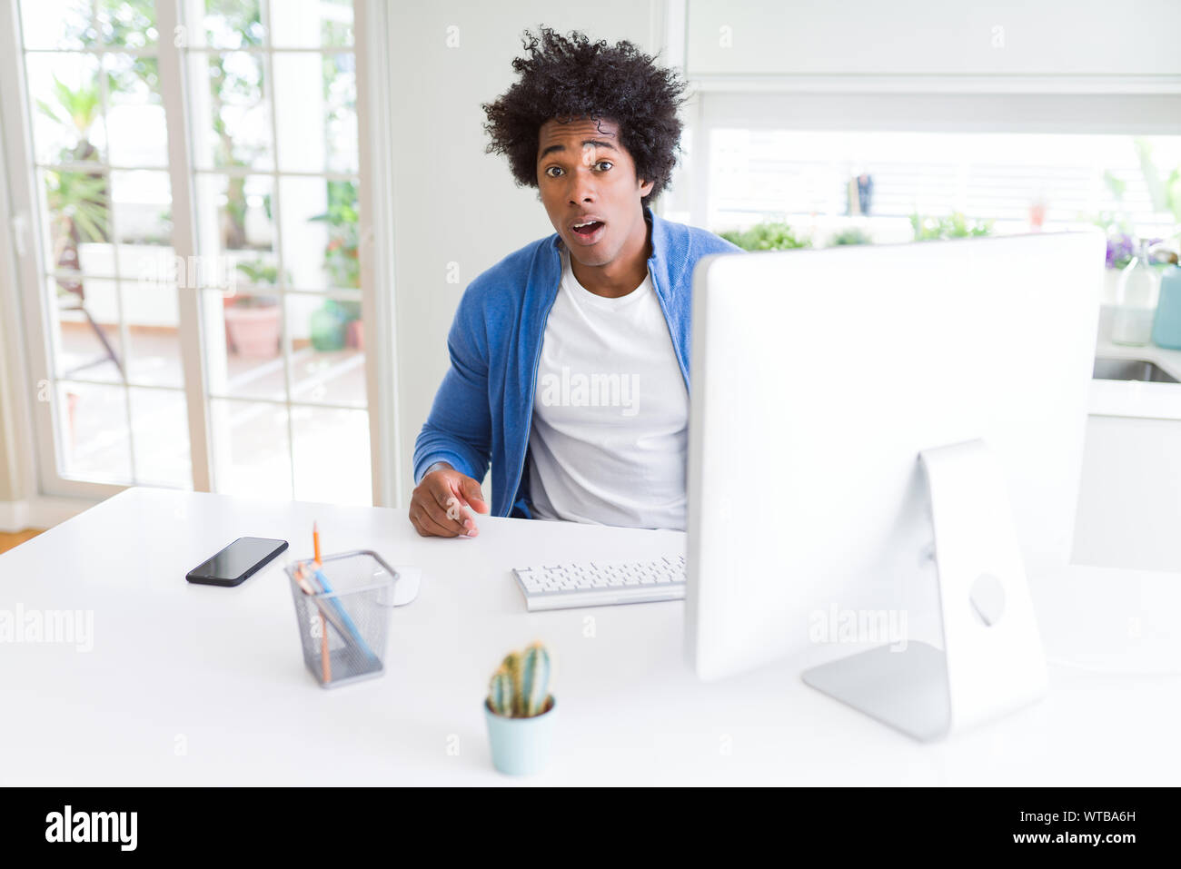 African American man working using computer afraid and shocked with ...