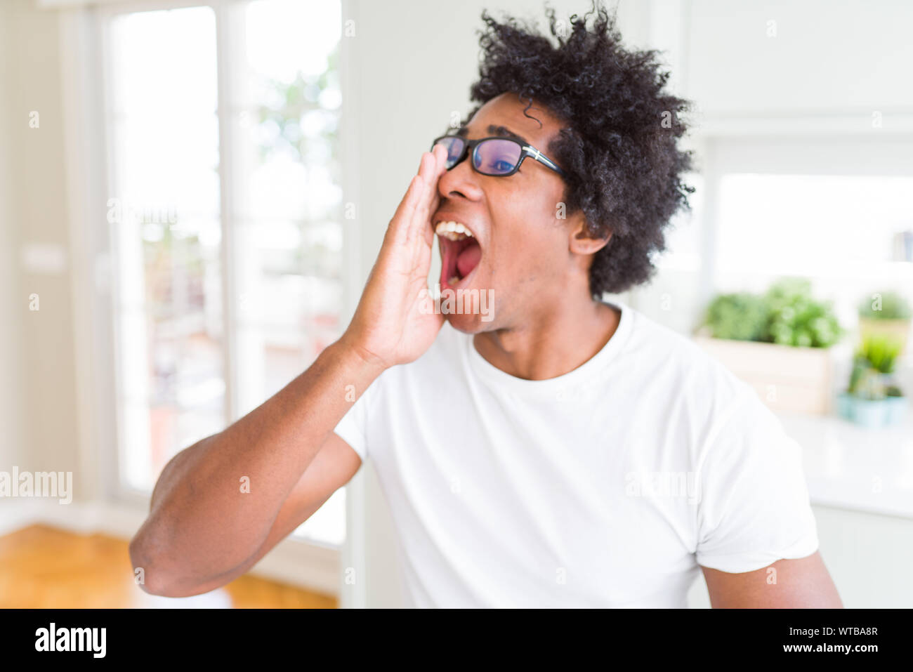 African American man wearing glasses shouting and screaming loud to ...