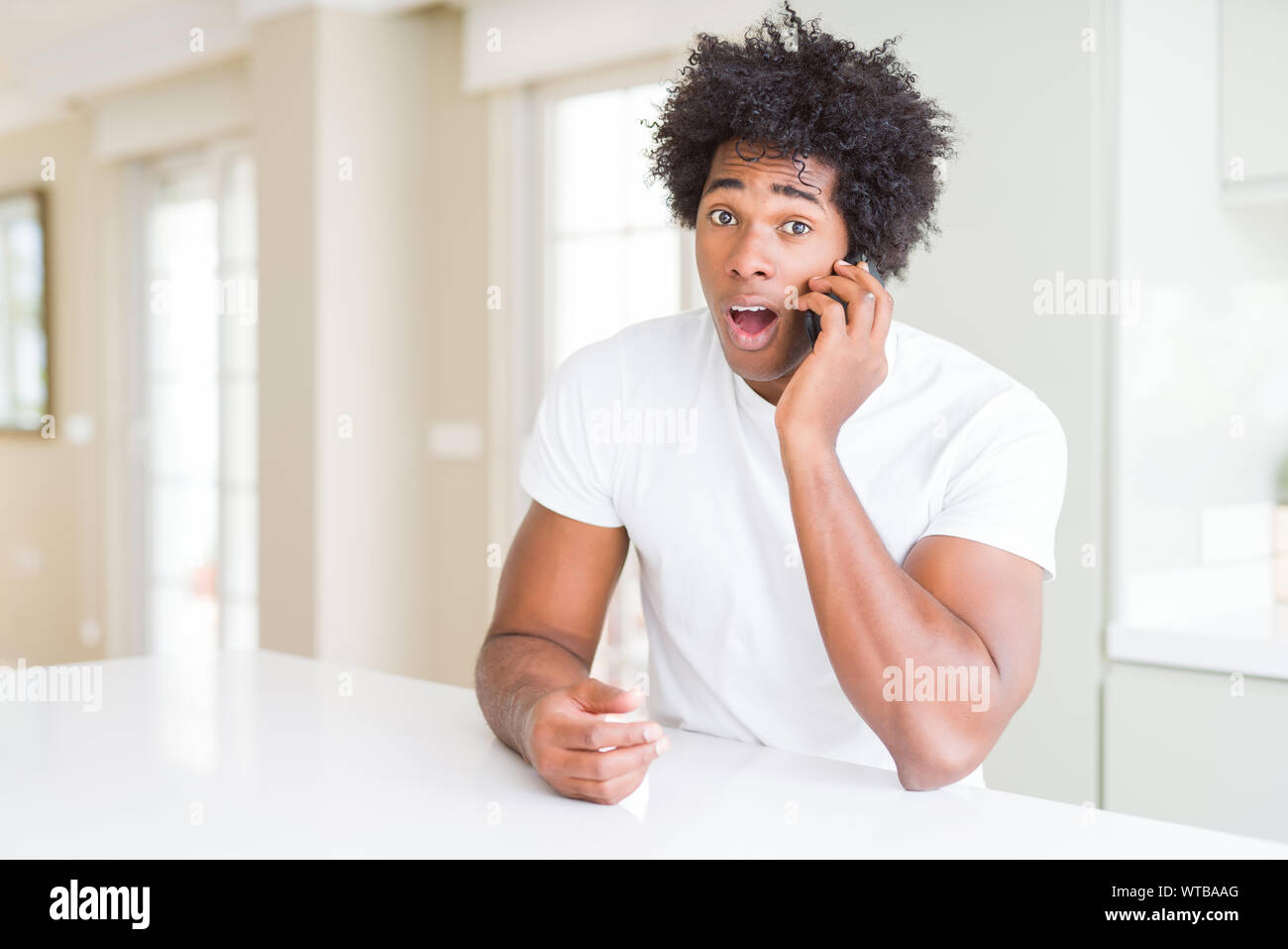 African American business man talking on the phone scared in shock with ...