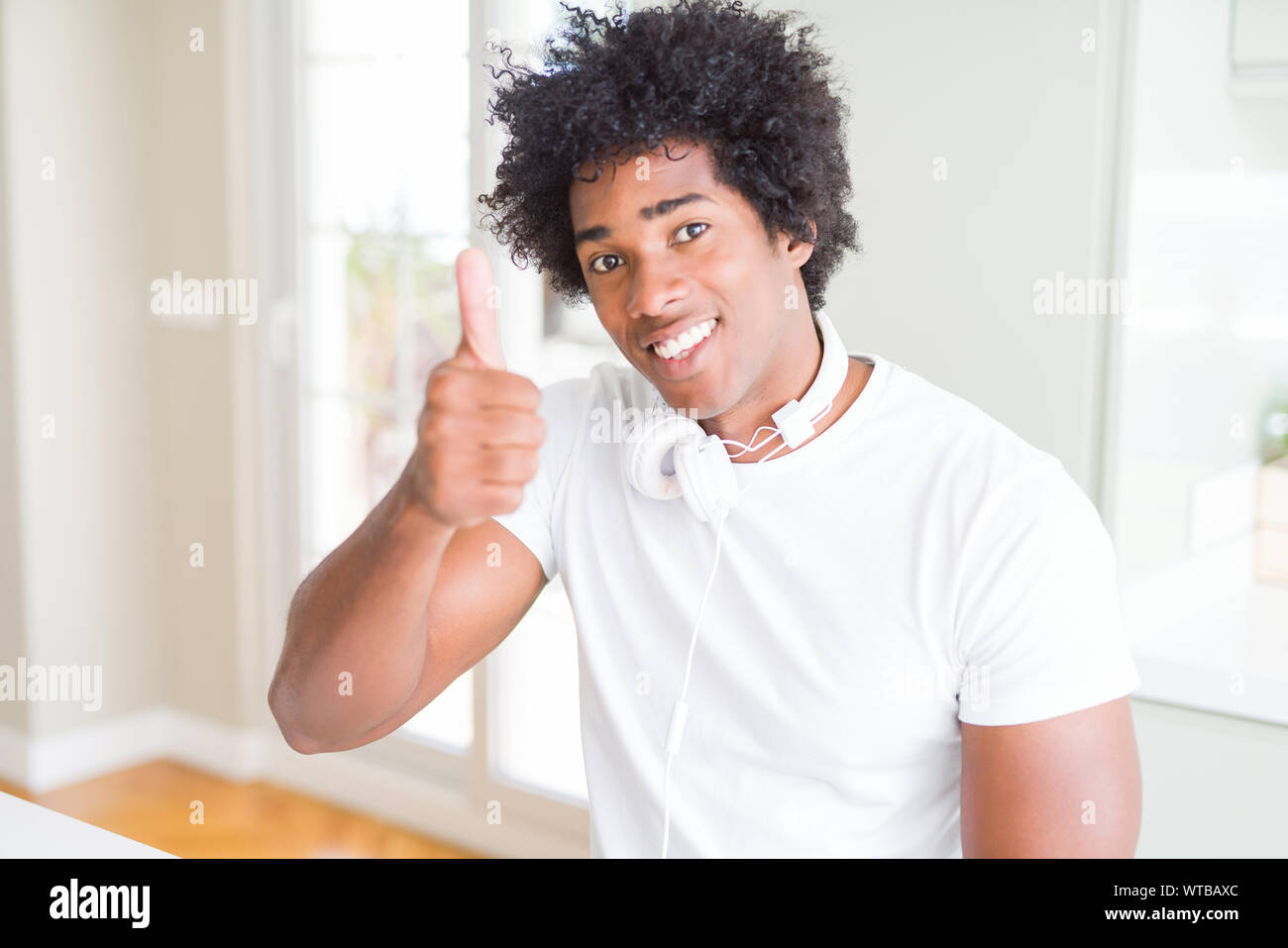 African American man wearing headphones listening to music doing happy ...