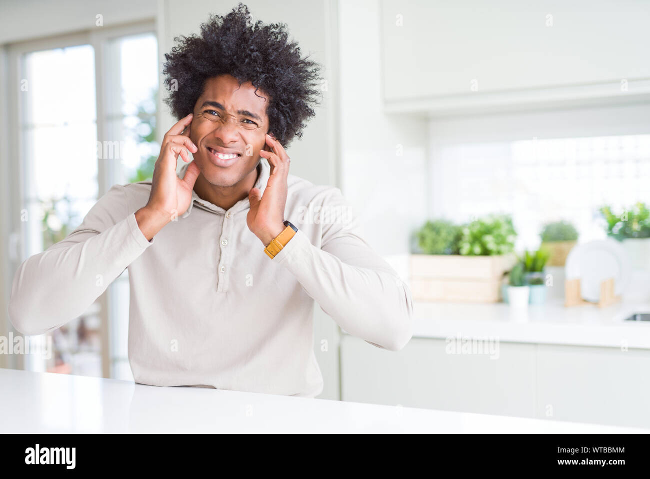 African American man at home covering ears with fingers with annoyed ...
