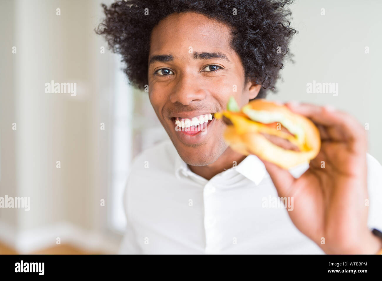 African American hungry man eating hamburger for lunch with a happy ...