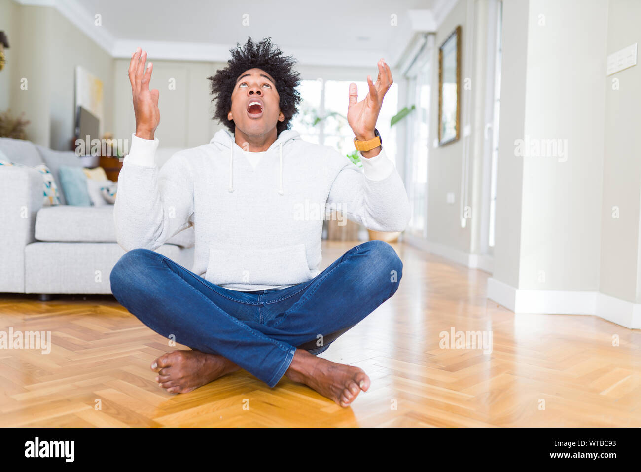 African American man sitting on the floor at home crazy and mad ...