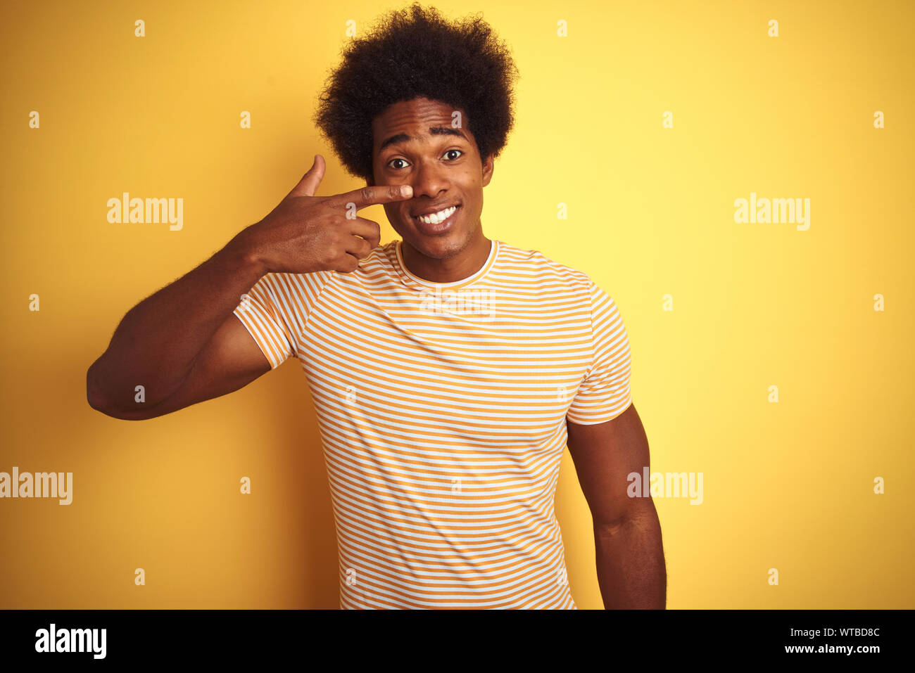 American man with afro hair wearing striped t-shirt standing over ...