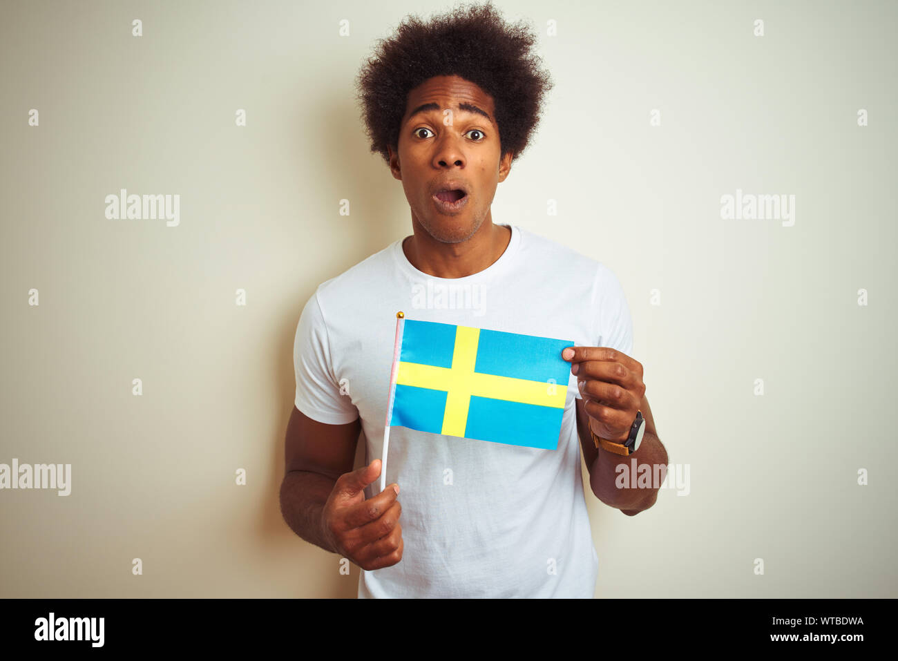 Young afro american man holding Sweden Swedish flag standing over ...