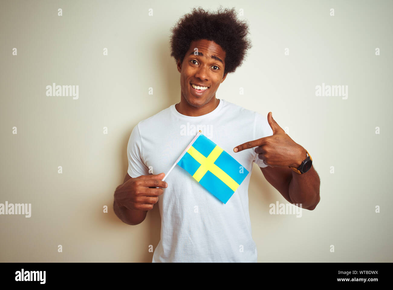 Young afro american man holding Sweden Swedish flag standing over ...