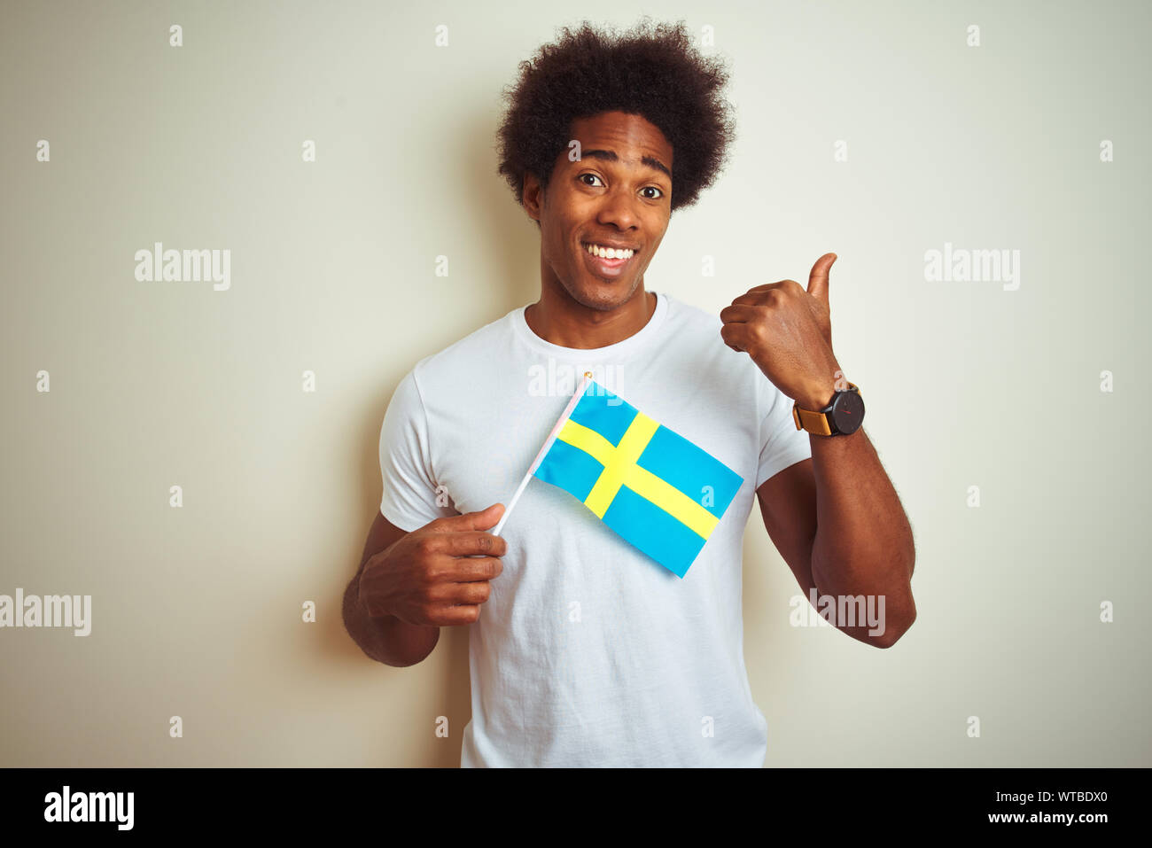 Young afro american man holding Sweden Swedish flag standing over ...