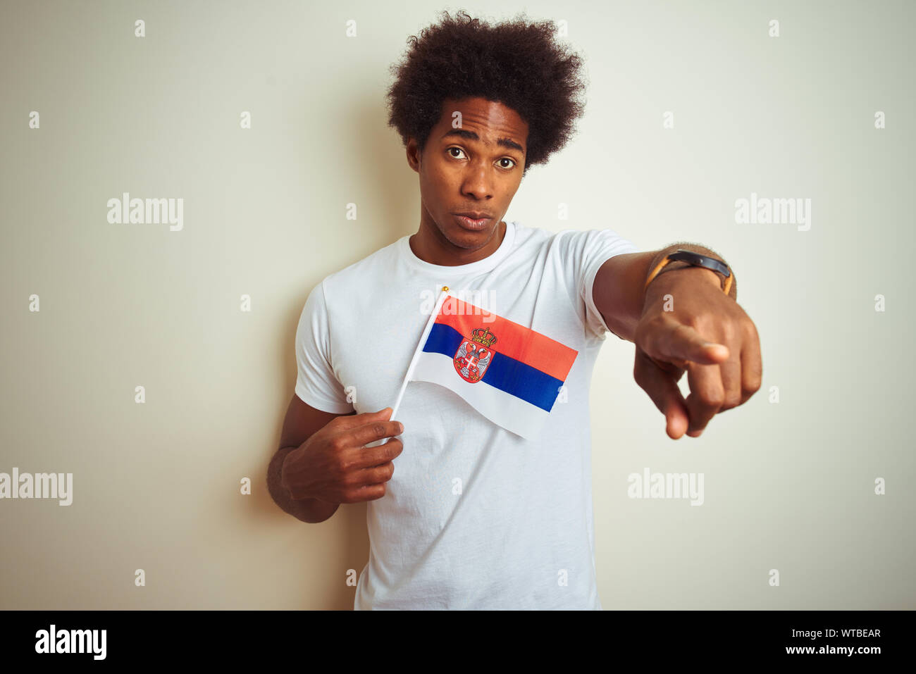 Young afro american man holding Serbia Serbian flag standing over ...