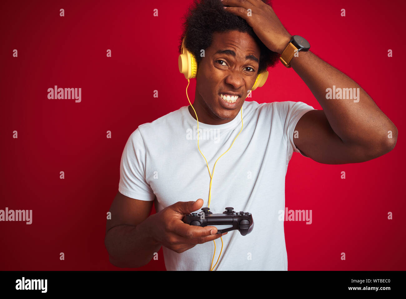 Afro gamer man playing video game using joystick headphones over ...