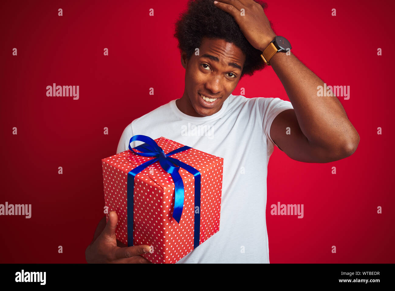 Young african american man holding birthday gift standing over isolated ...