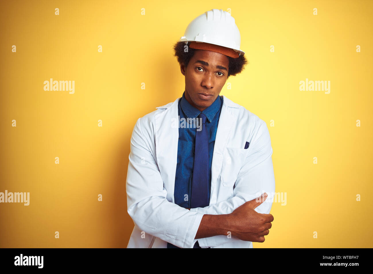 Afro american engineer man wearing white coat and helmet over isolated ...