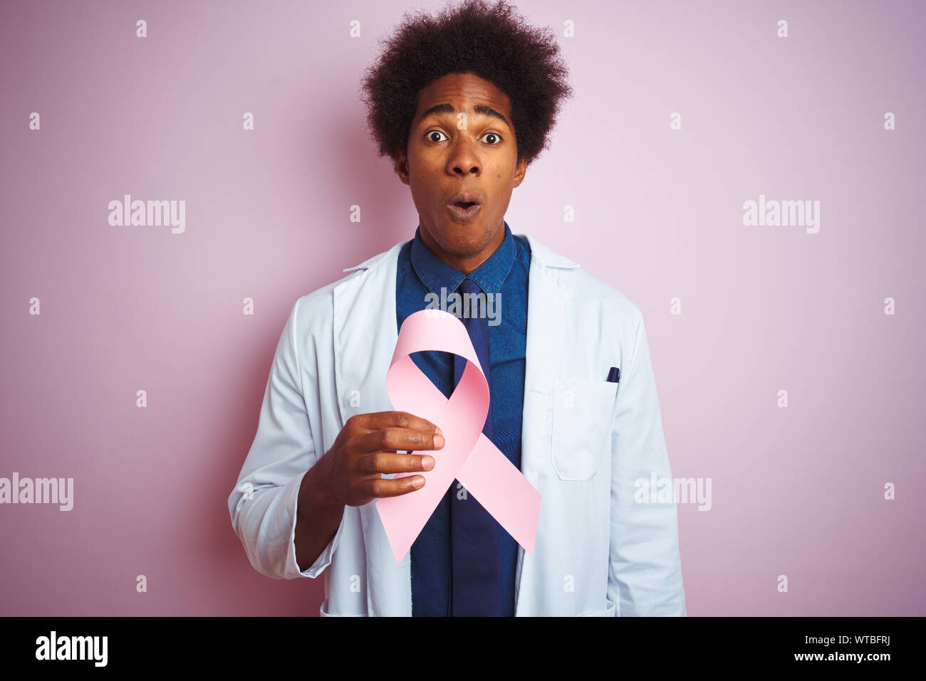 Young afro american doctor man holding cancer ribbon standing over ...